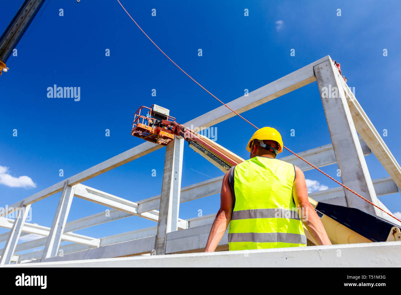 View from behind on construction worker with safety vest and yellow ...