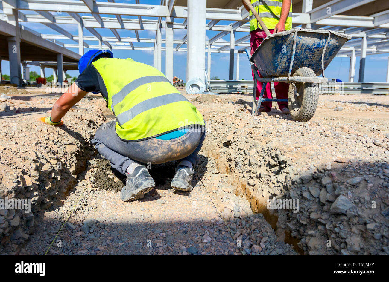 Mason is using a trowel to align first level of the concrete foundation ...