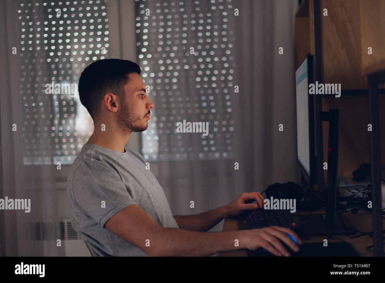 Programer working on his computer while the screen light reflects on ...
