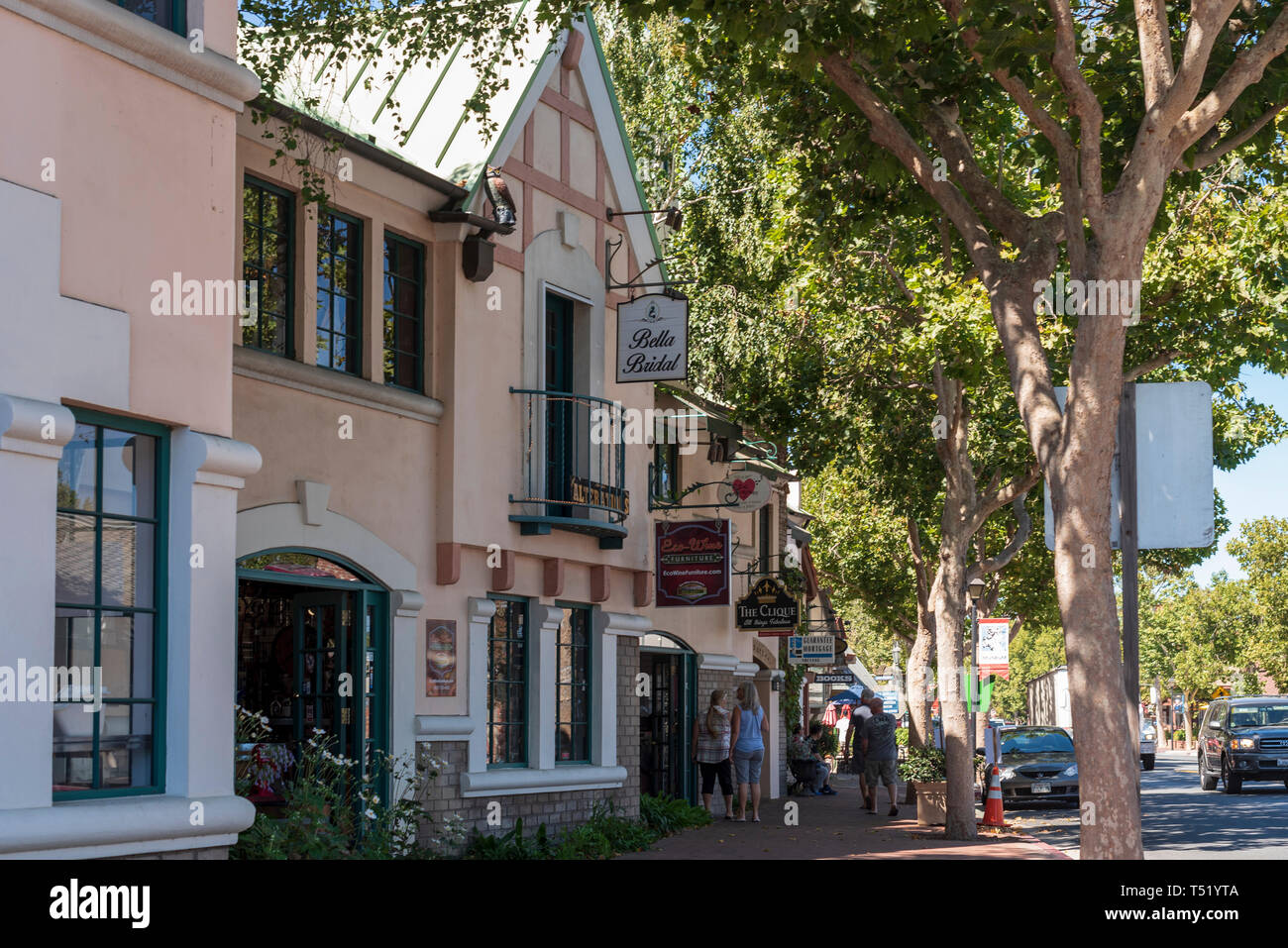 Tourists on small town street with various shops. Street has shade ...