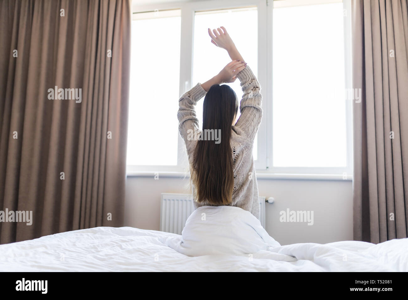 Rear view of woman stretching in bed after wake up in morning with ...