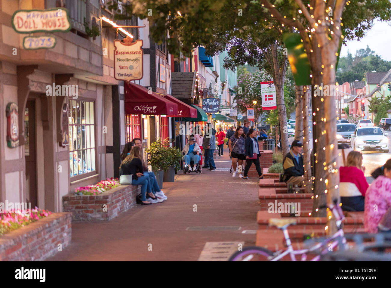 Sidewalk with store fronts, business signs and tourists. Flower boxes ...