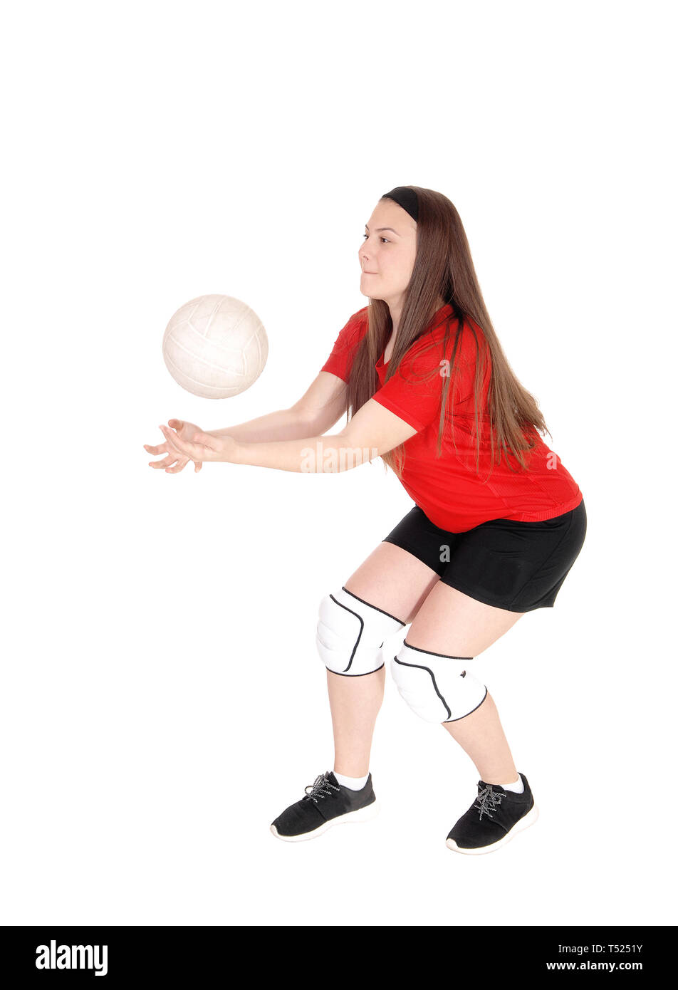 A young teenage girl in her uniform playing volley ball try to catch ...