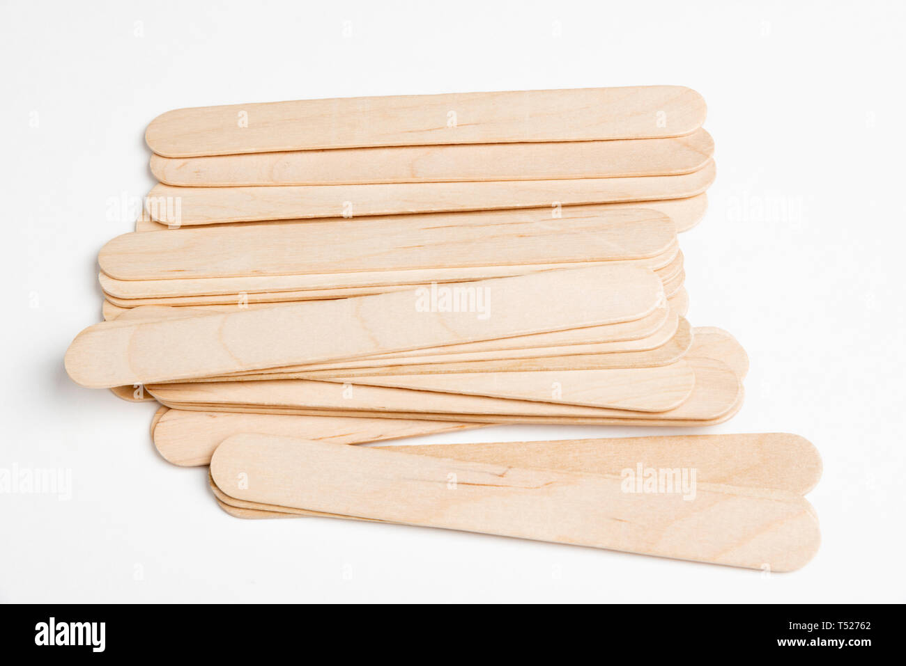 A stack or array of unused thick wooden craft sticks set on a plain ...