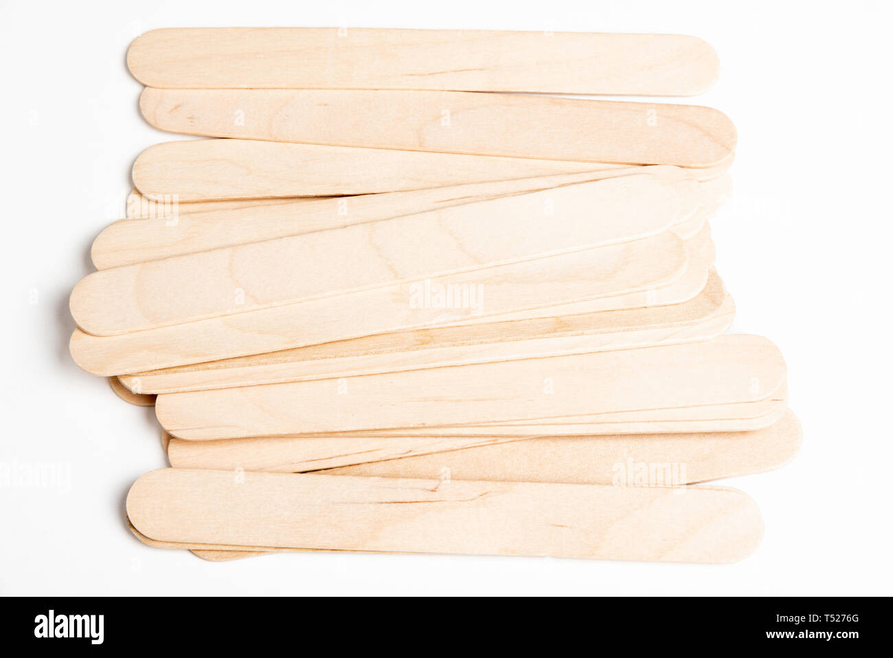 A stack or array of unused thick wooden craft sticks set on a plain ...