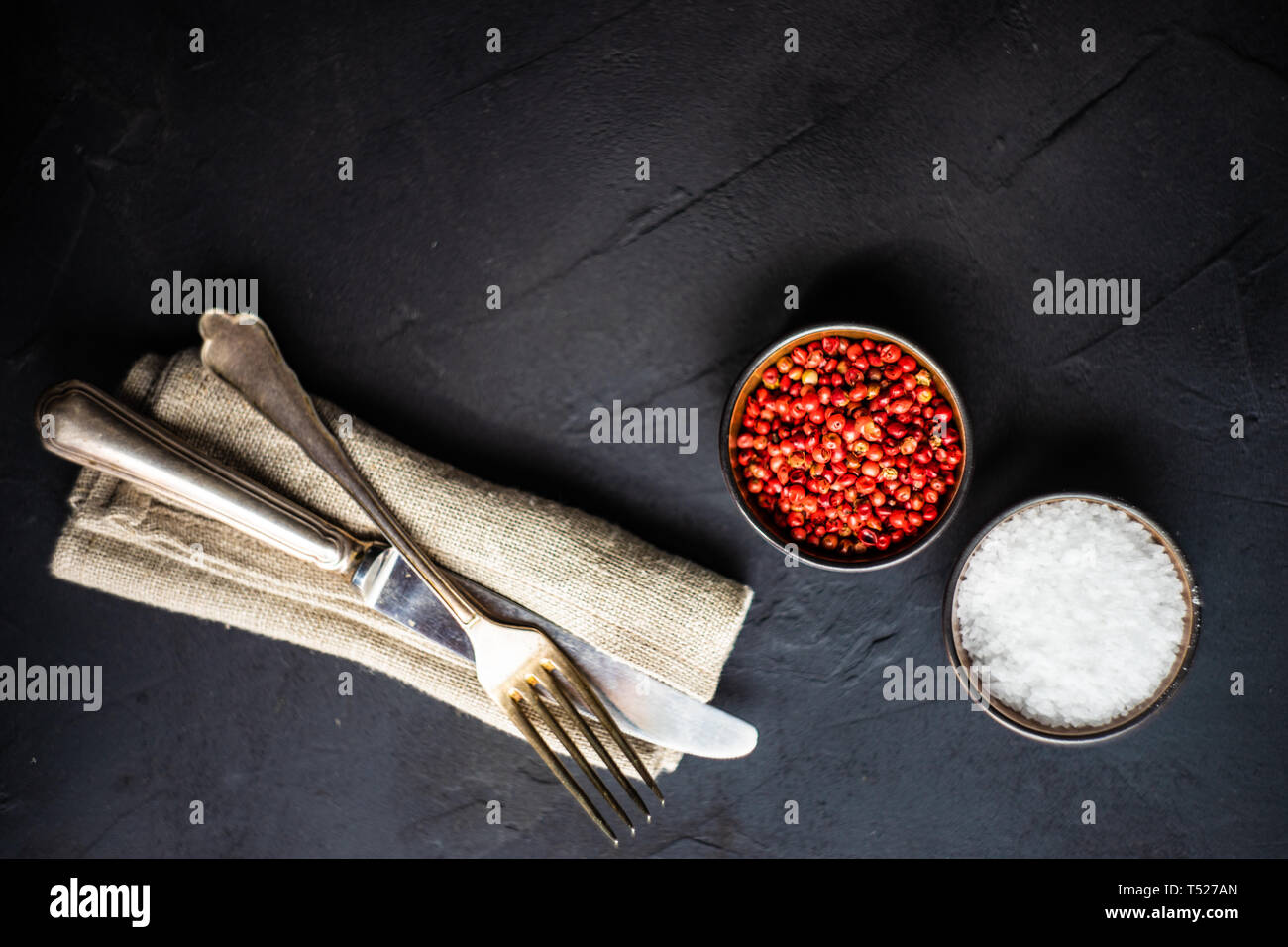 Vintage cutlery set and bowls with pepper and salt on stone background ...