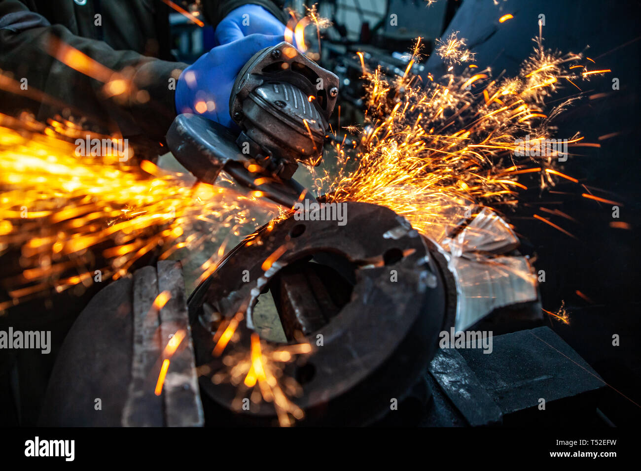 A close-up of a car mechanic using a metal grinder to cut a brake disk ...