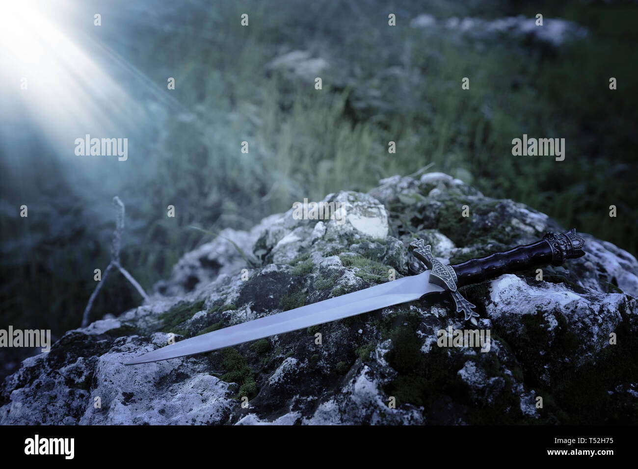 mysterious and magical photo of silver sword over the stone covered ...