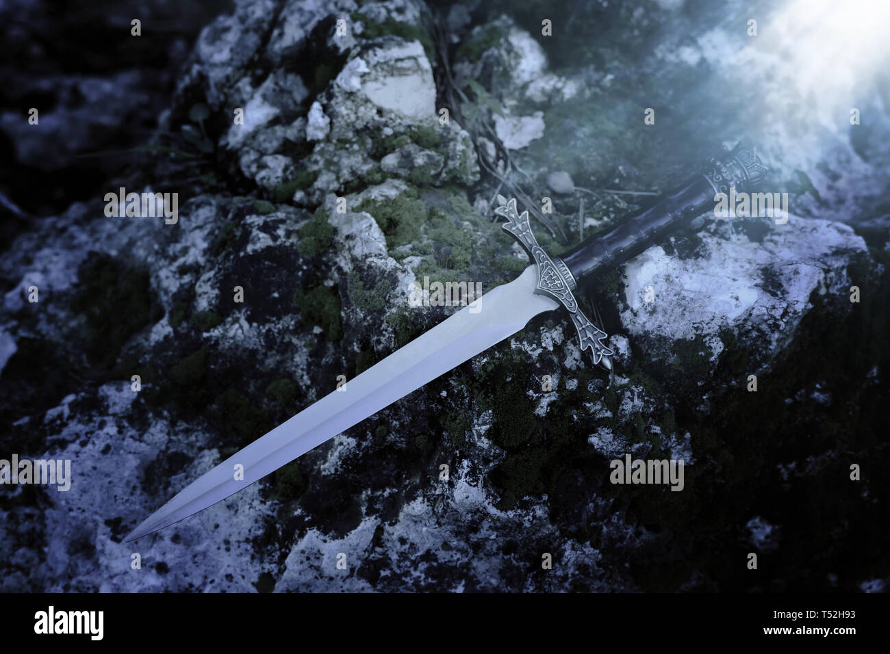 mysterious and magical photo of silver sword over the stone covered ...