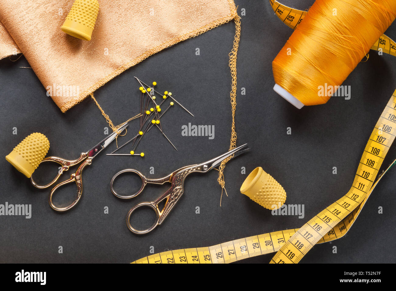 sewing tools thread with scissors and measuring tape on dark Stock ...