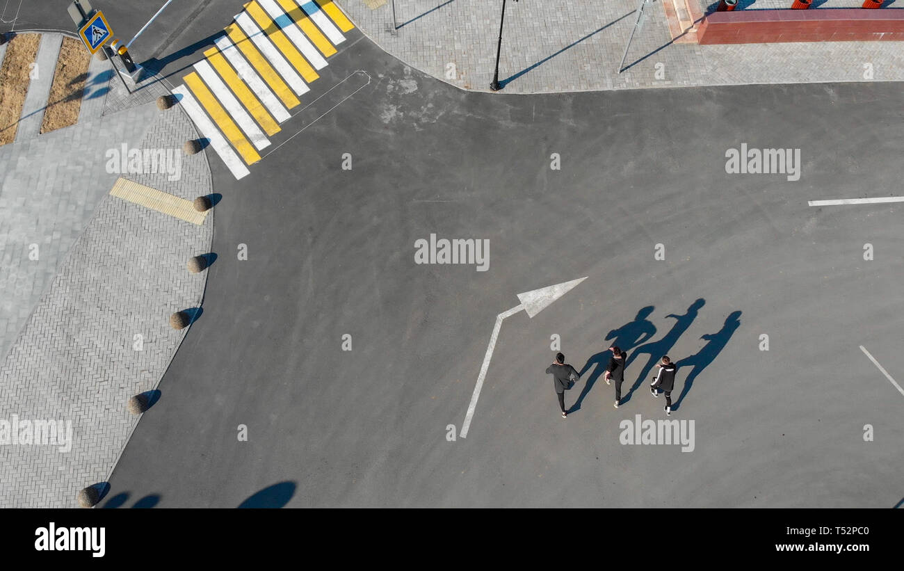 Aerial view of urban streets. Crosswalk. Three men walking on the road ...