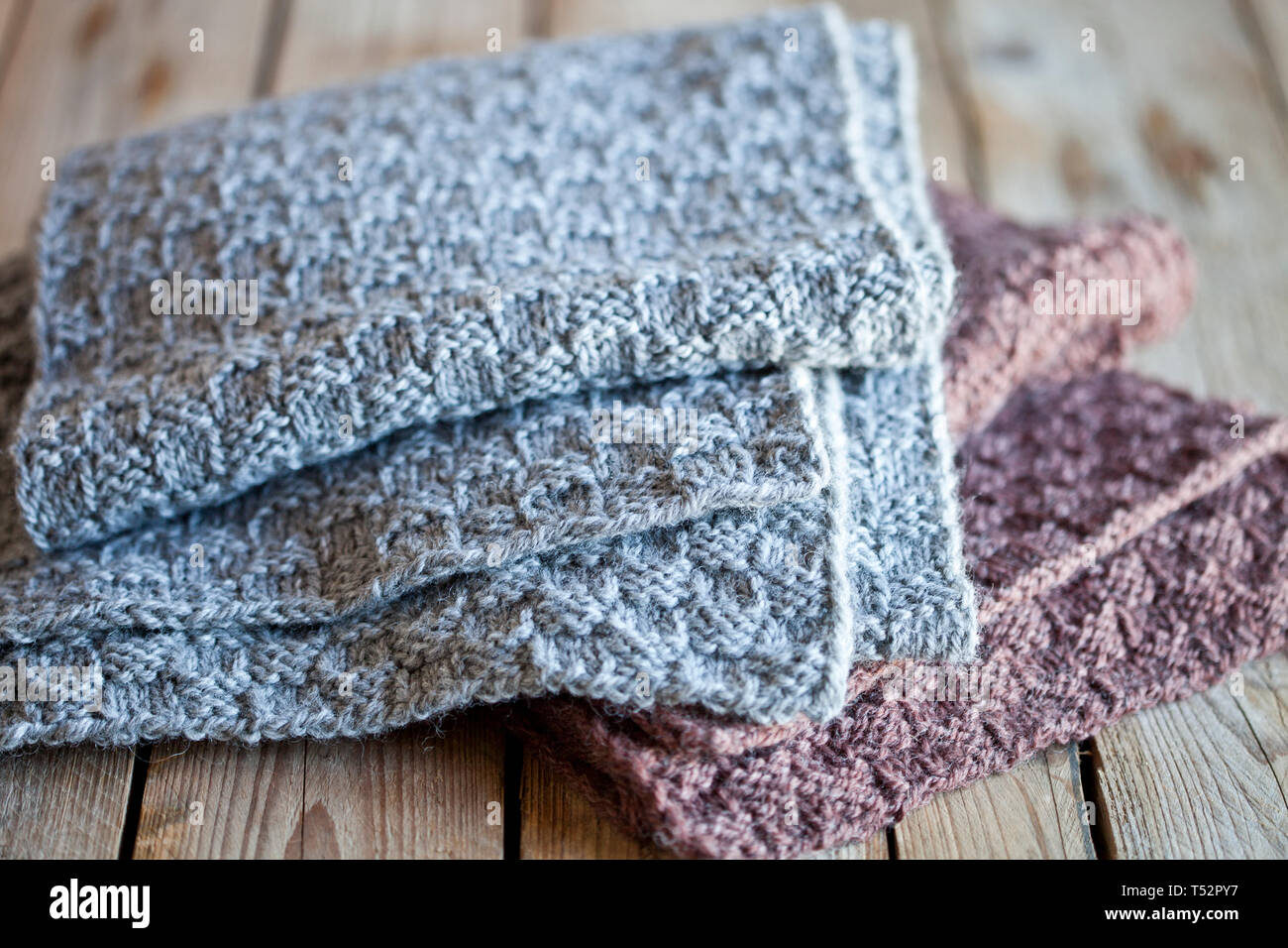 Knitted woolen grey and brown scarves on wooden background Stock Photo ...