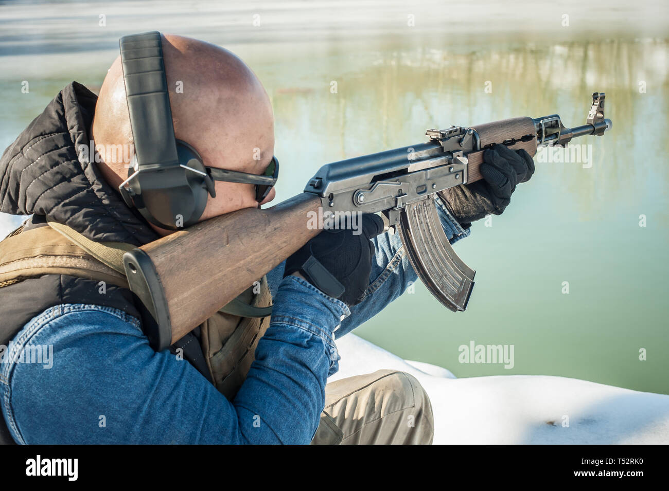 Civilian in crouching shooting position shooting from rifle machine gun ...