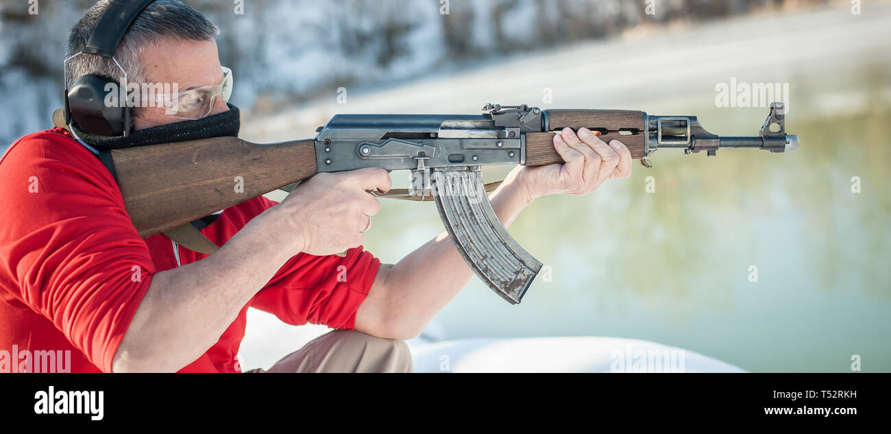 Civilian in crouching shooting position shooting from rifle machine gun ...
