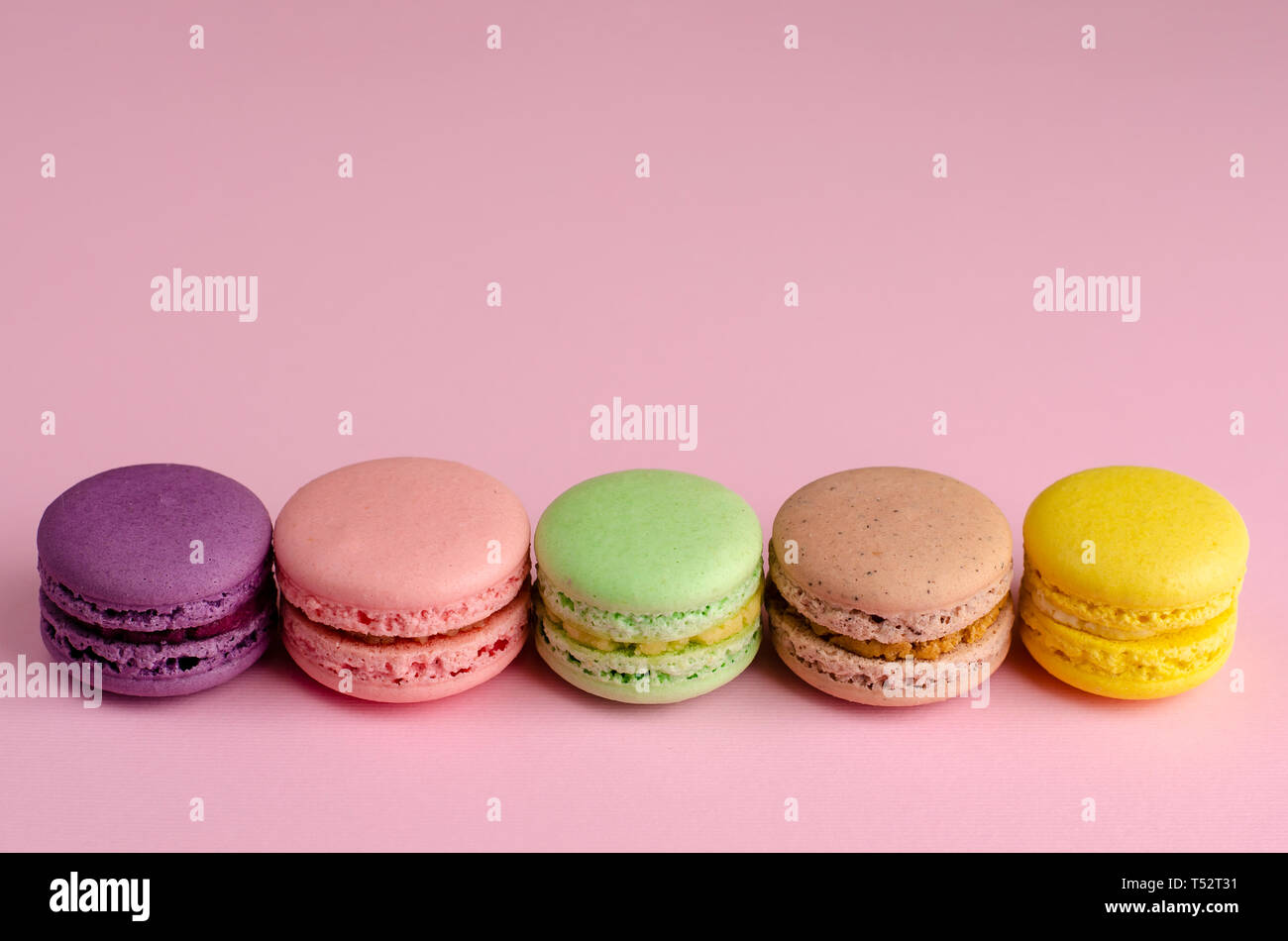 Colorful sweet french dessert macaroon or macaron on pastel pink ...
