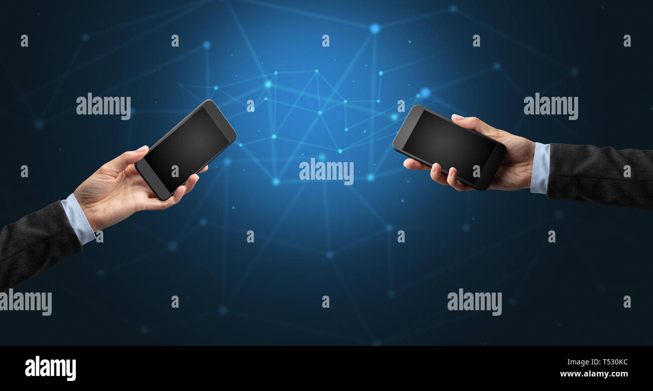Close up of two hands holding smartphones to each other, wireless ...
