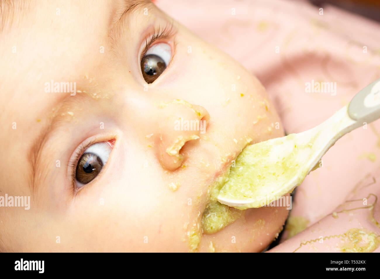 Close-Up portrait of cute baby with infant puree on face at home Stock ...