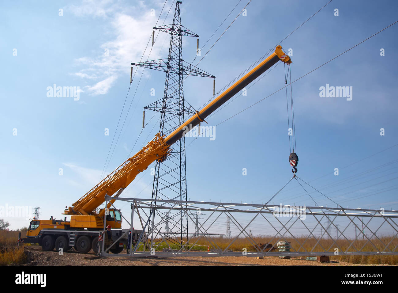 A crane installs a high voltage power line in an industrial suburb ...