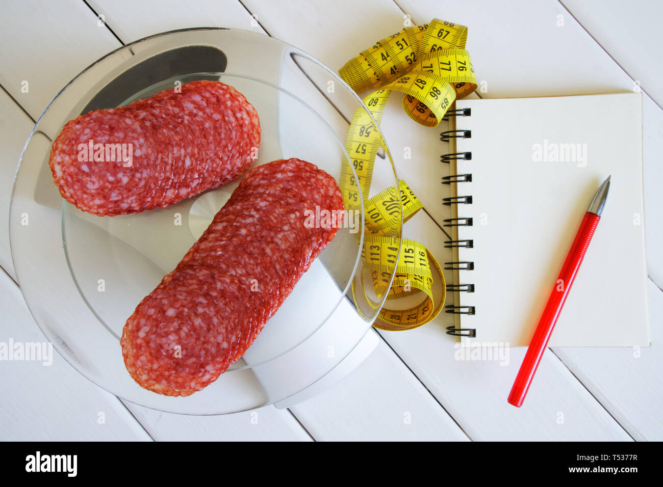 Pieces of smoked sausage on a kitchen scale, next to a tape measure, a ...