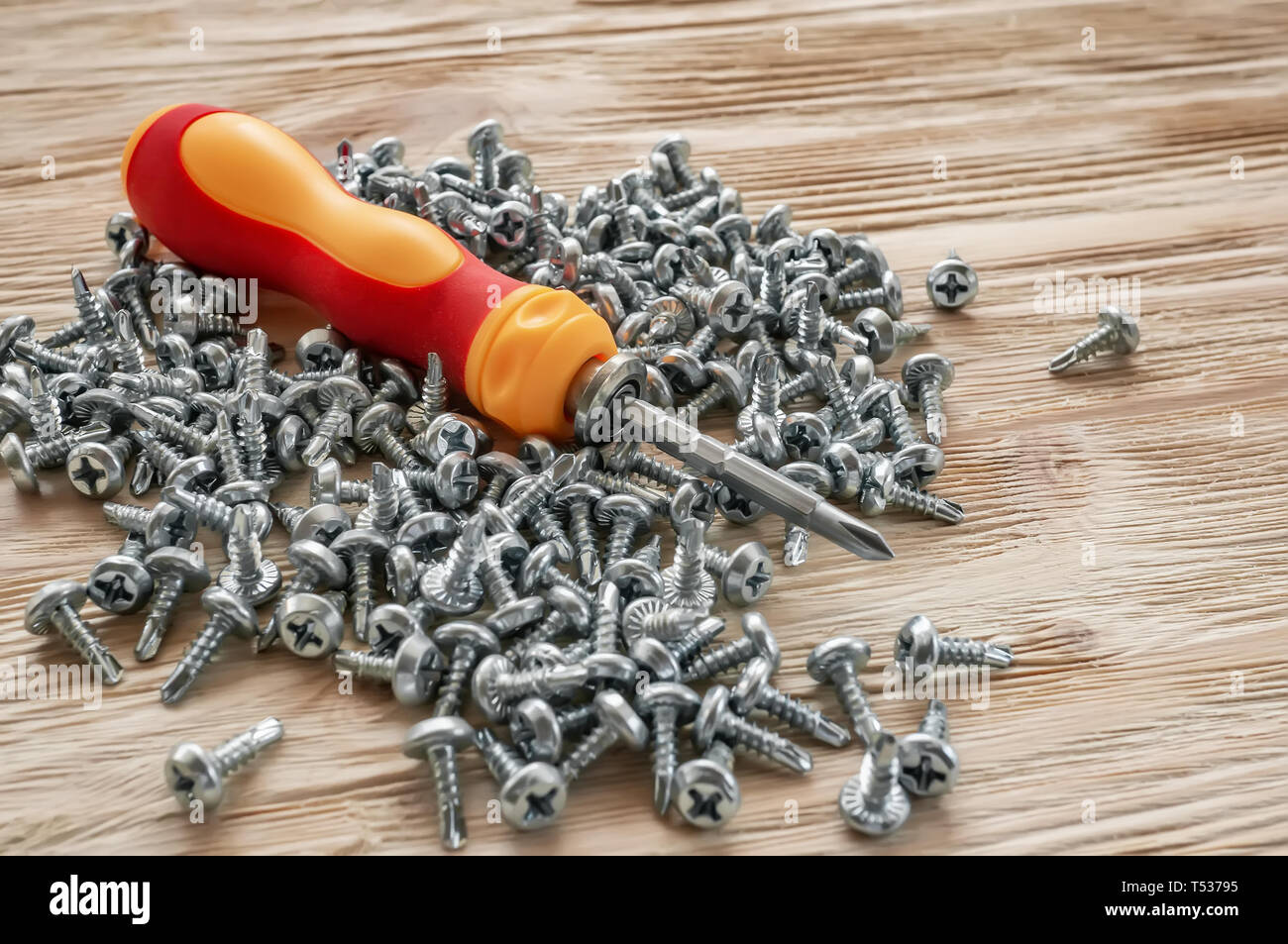 Manual screwdriver screws and dowels on a wood background Stock Photo ...