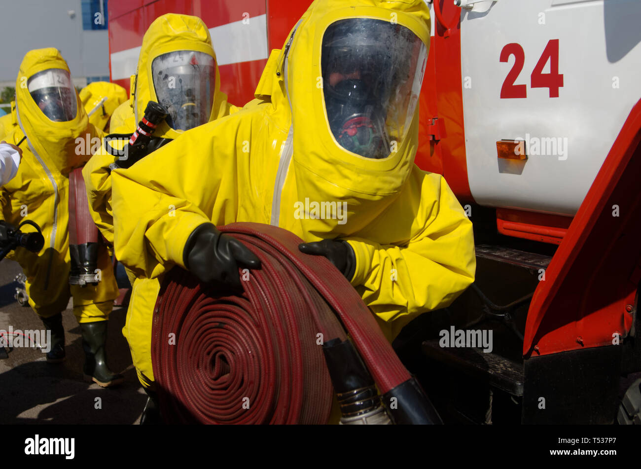 Firefighters in protective suits, gas masks and a hose are getting ...