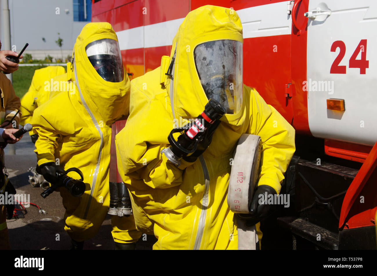 Two firefighters in protective suits and gas masks are preparing for ...