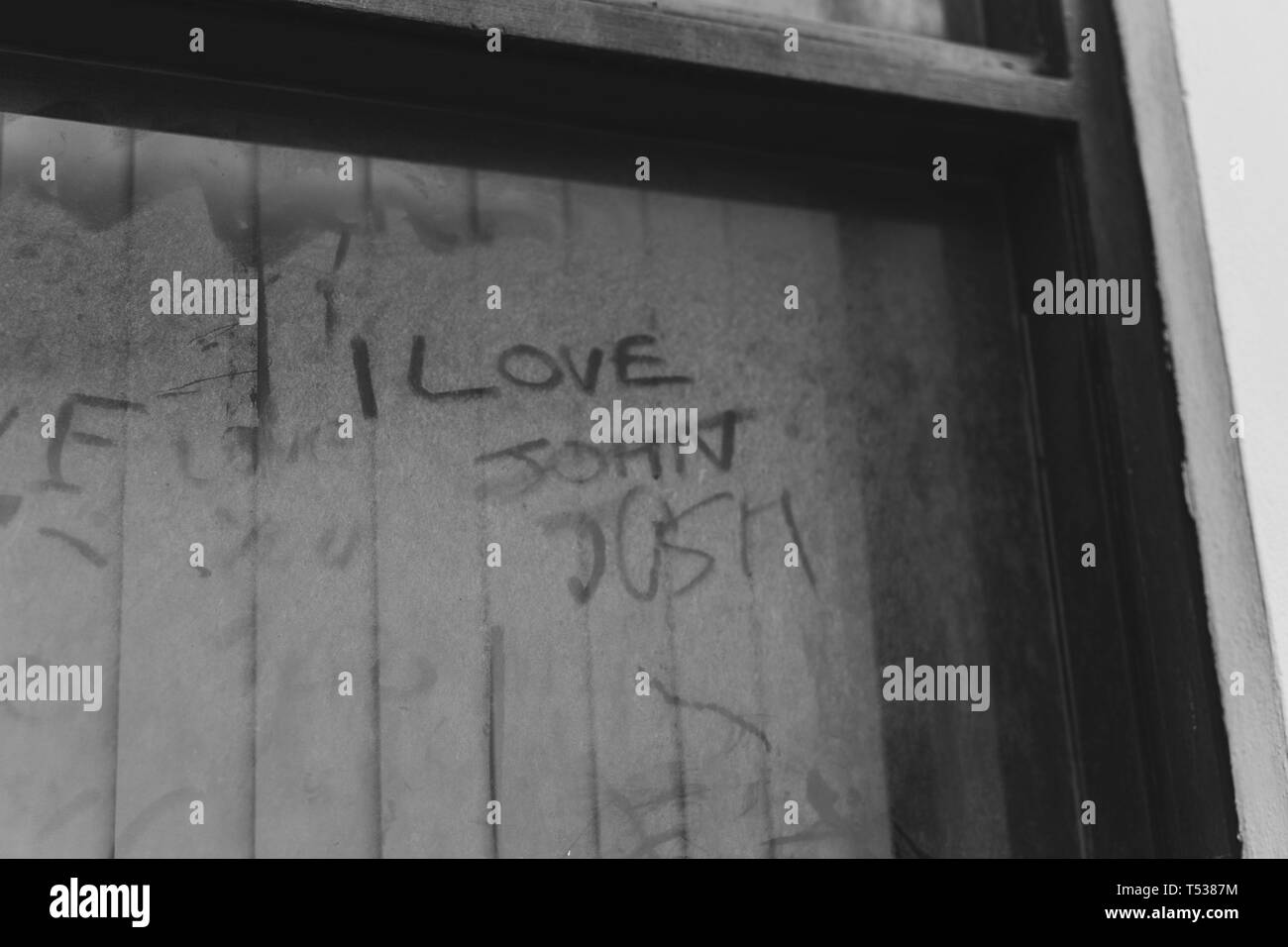 Text written in dust on window reading 'I love John' with 'John ...