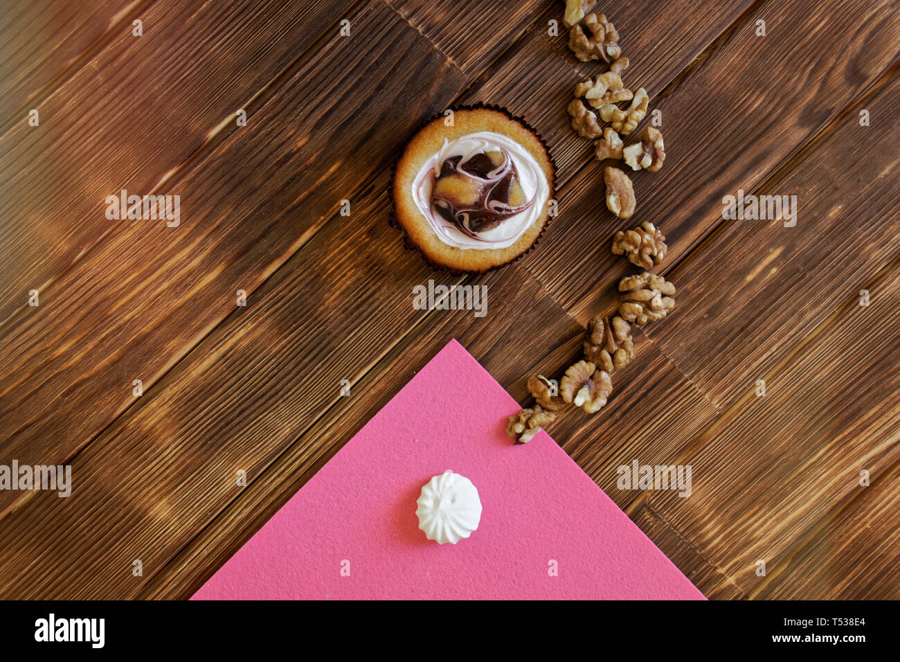 Round fruit cream cake, meringue and peeled walnuts on a pine planks ...