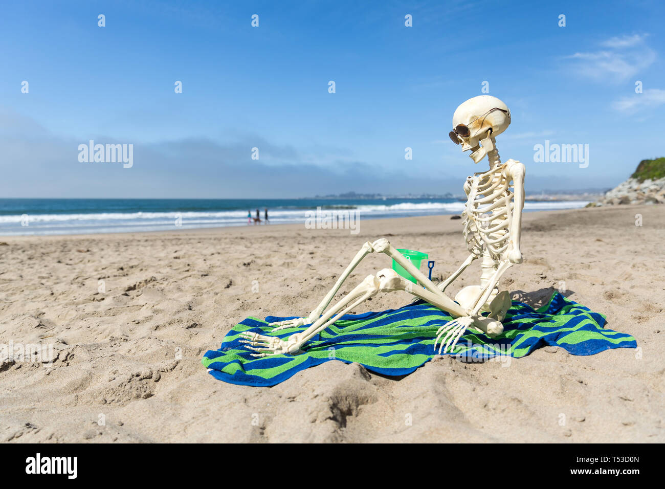 Skeleton sits on a beach towel relaxing in the sand Stock Photo - Alamy