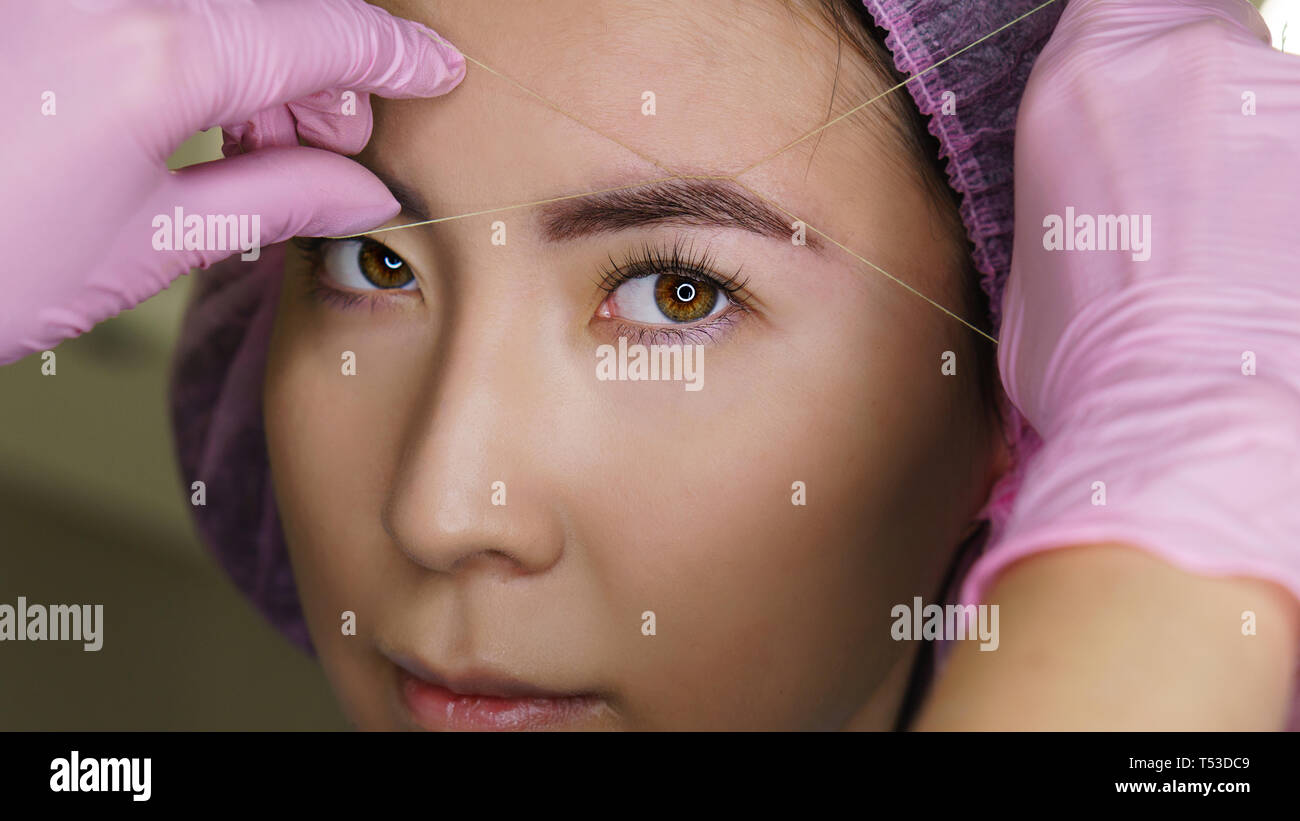 Microbleeding and eyebrow architecture. Beautician forms lines of ...