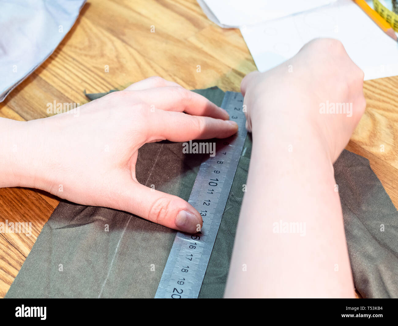 dressmaker draws a pattern on fabric with ruler and soap on cutting ...