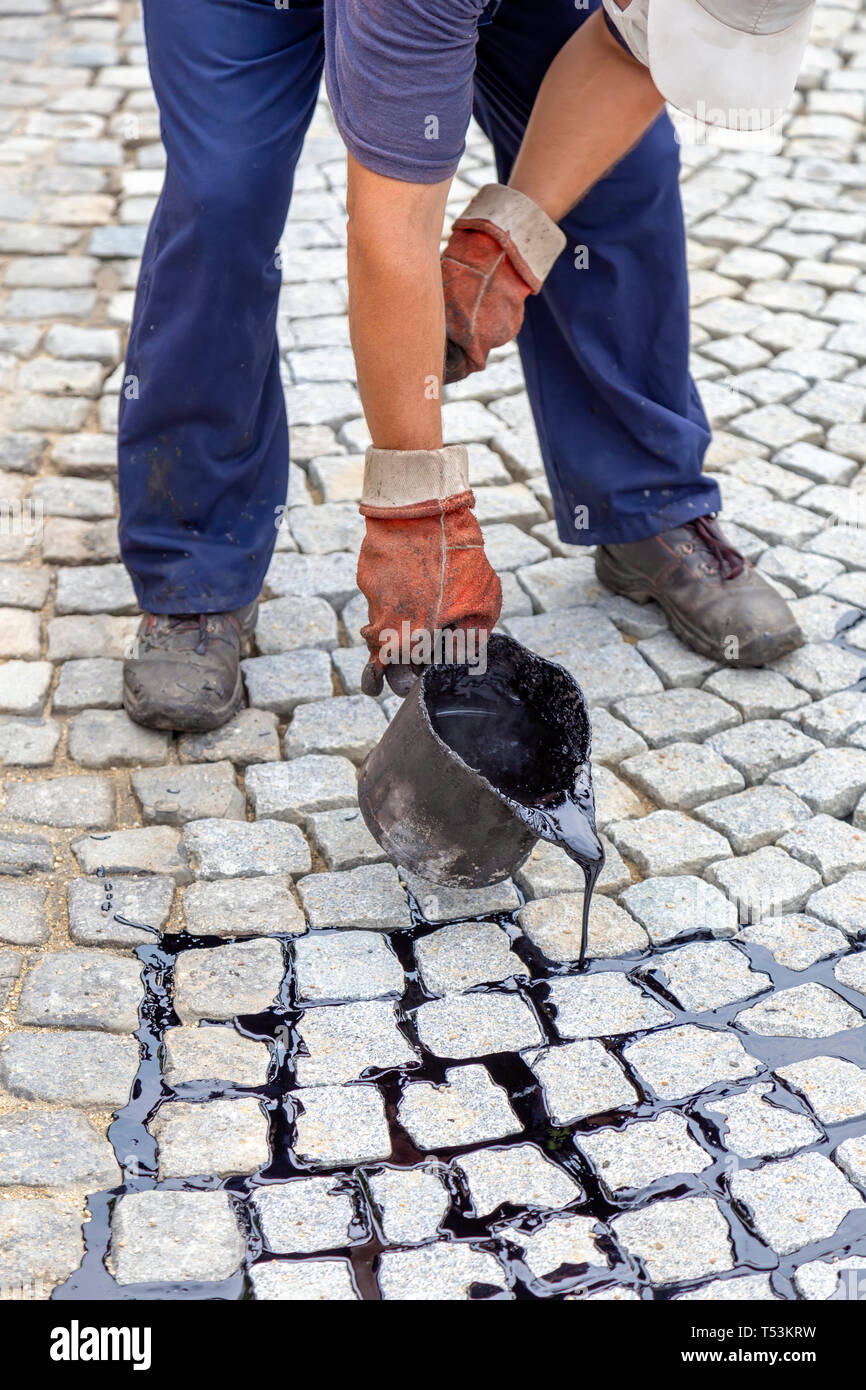 Crew member pouring molten pitch from a tar bucket. Traditional pitch ...