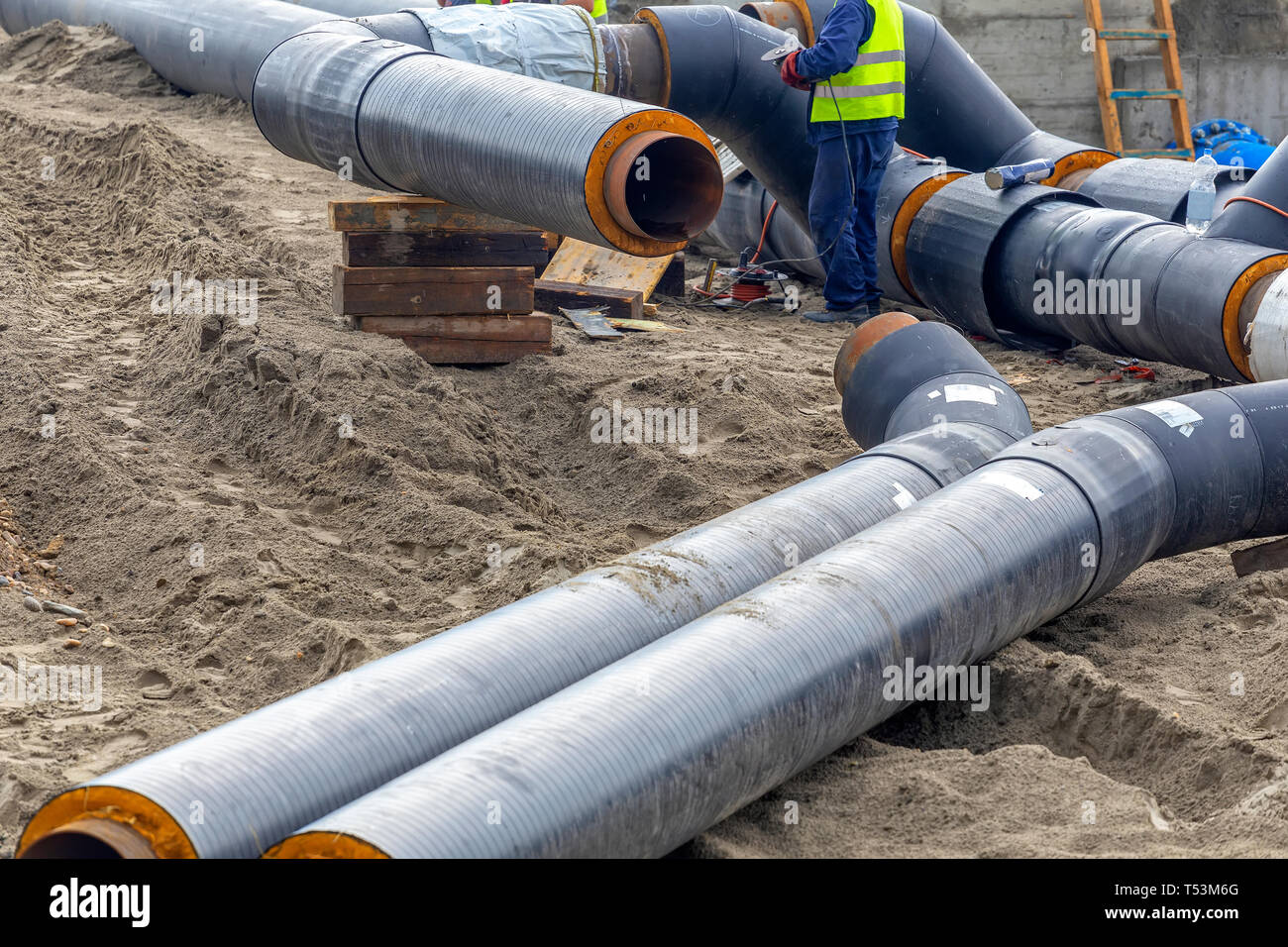 Metal worker grinding steel pipe, using grinder to work on new pipeline ...