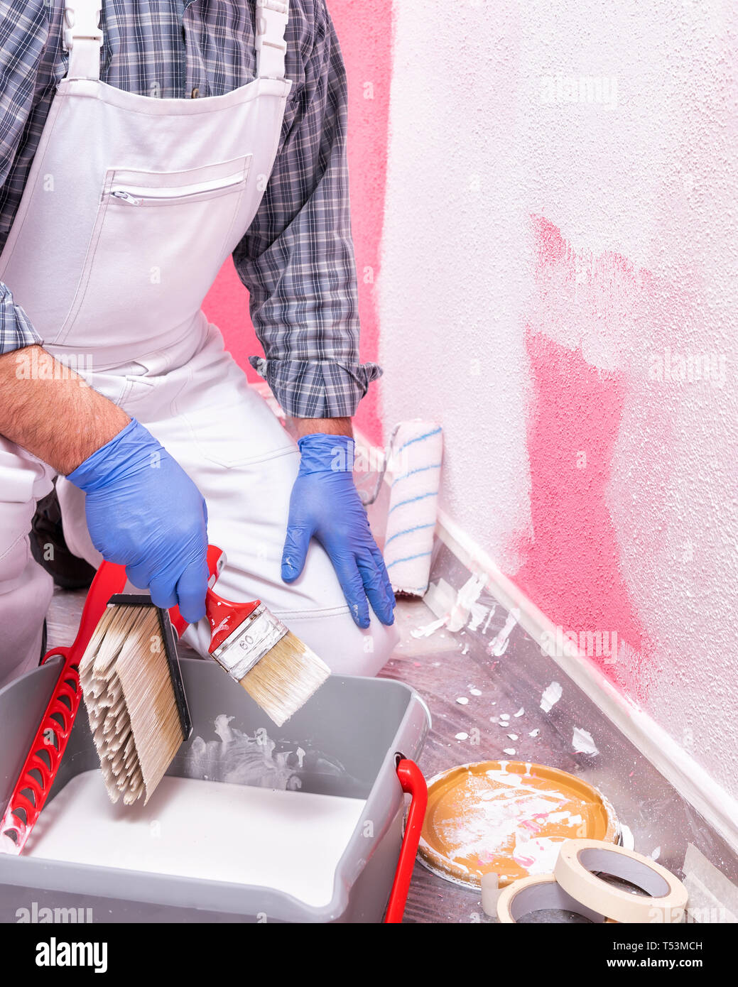 Caucasian house painter worker in white overalls, painting the pink ...