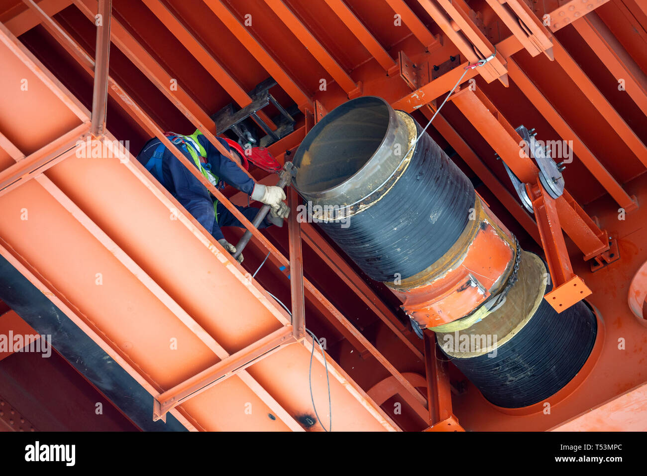 Workers installing district heating pipeline system under metal bridge ...
