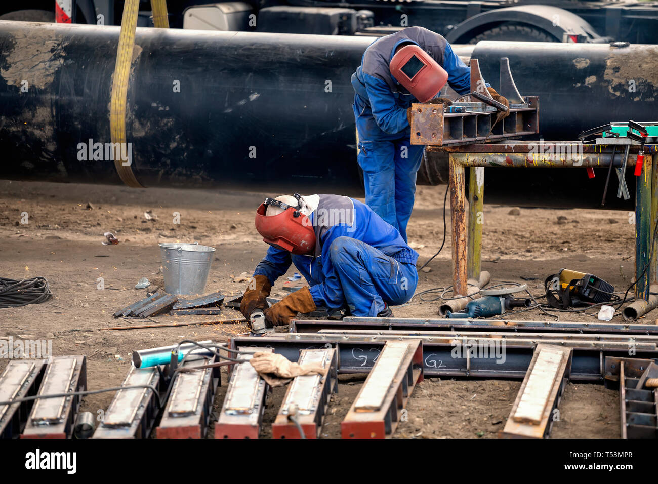 Workers welding and grinding, wearing safety gears and dark glass for ...