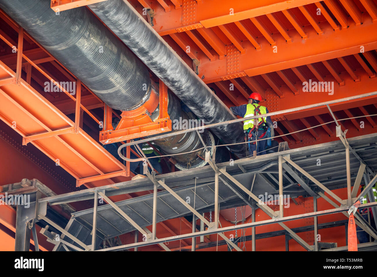 Workers welding work on district heating pipes under metal bridge. Big ...