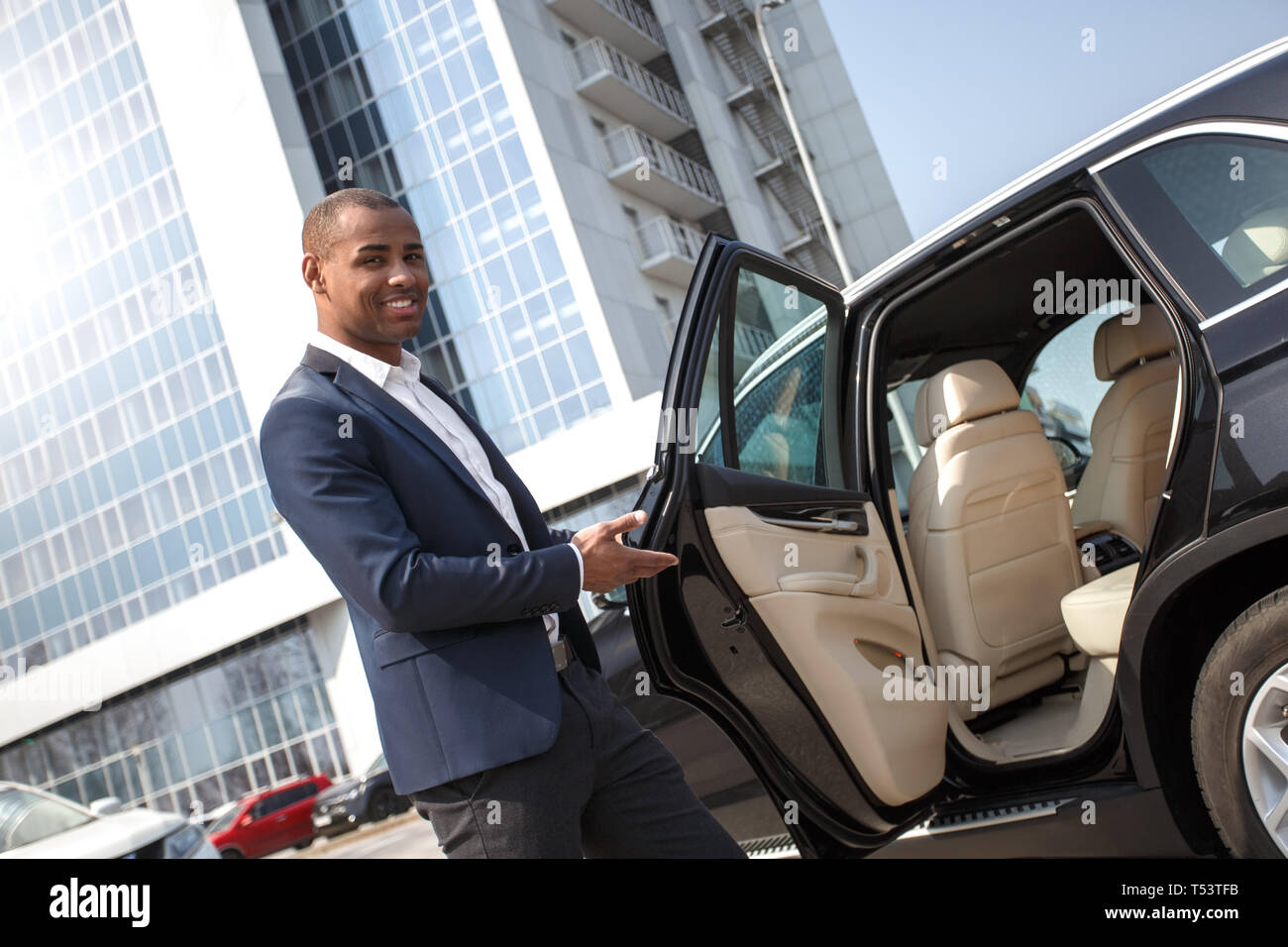 Young african american man personal driver standing near car opening ...