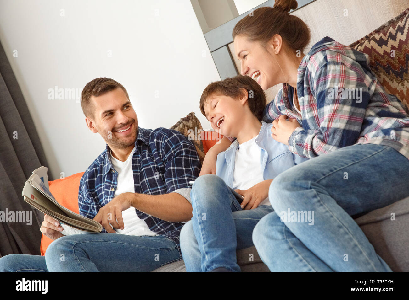 Mother Father And Son At Home Sitting On Sofa In Living Room Together
