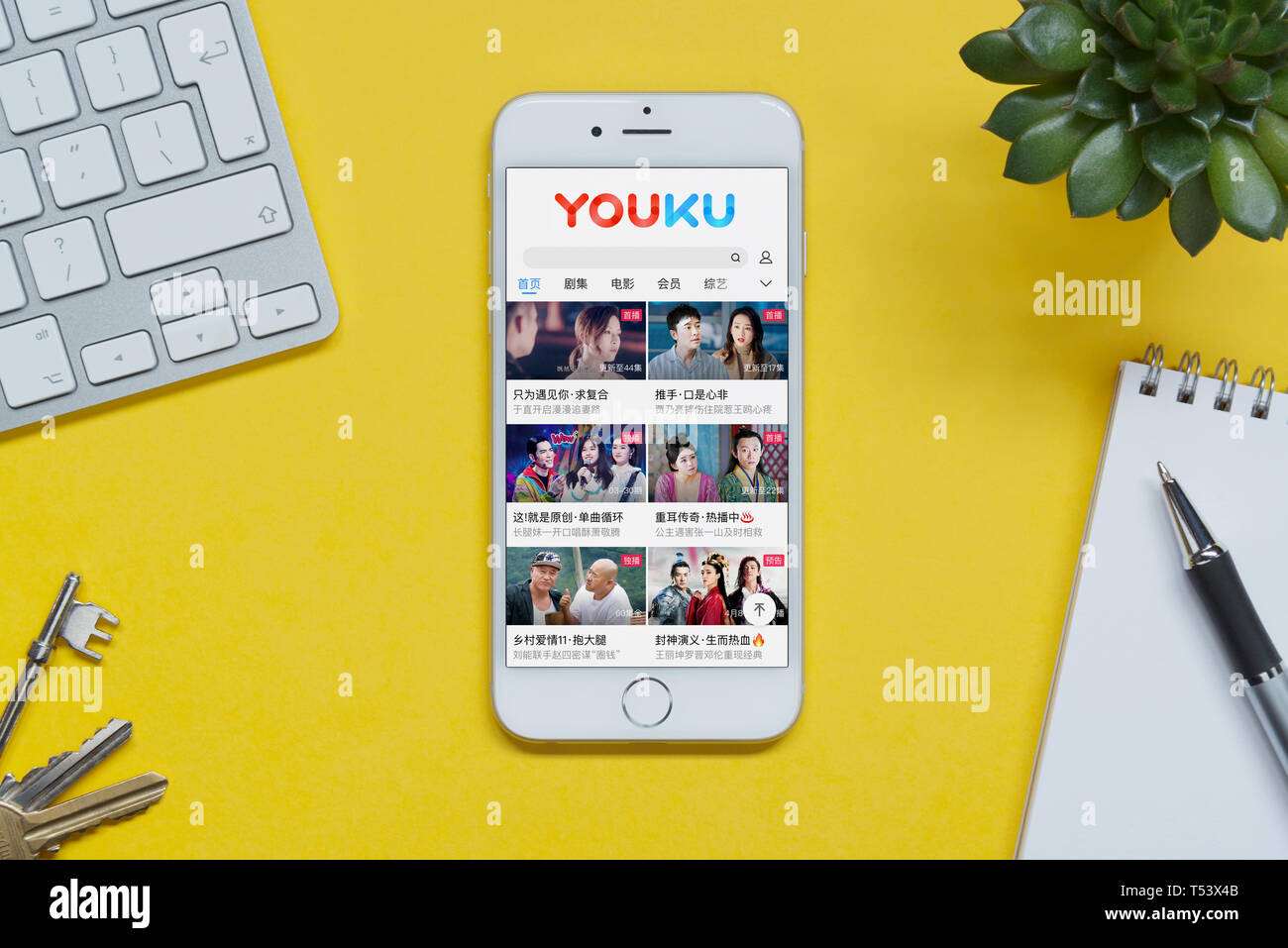 An iPhone showing the Youku website rests on a yellow background table ...