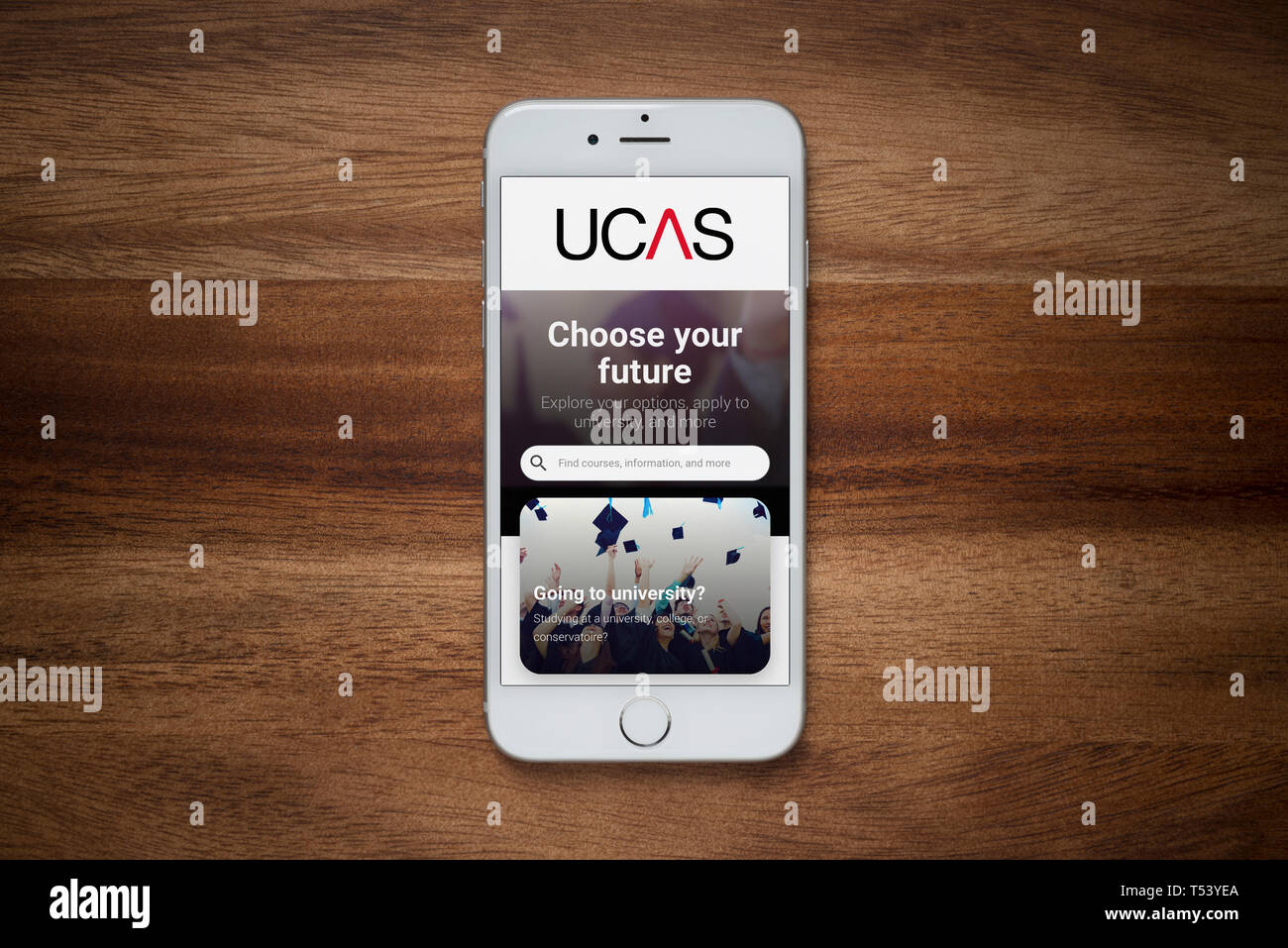 An iPhone showing the Ucas website rests on a plain wooden table ...