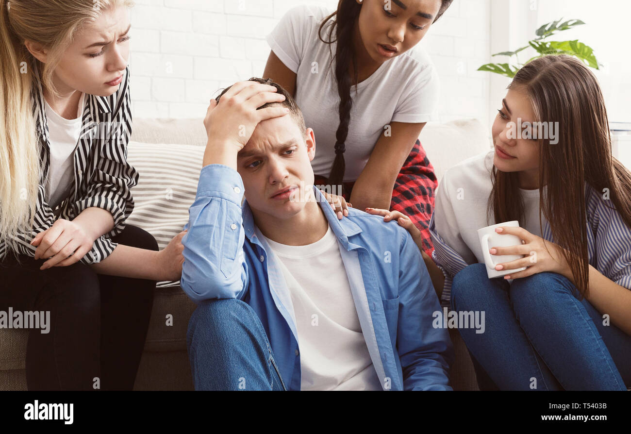 Young people comforting their upset friend, discussing problems at home ...