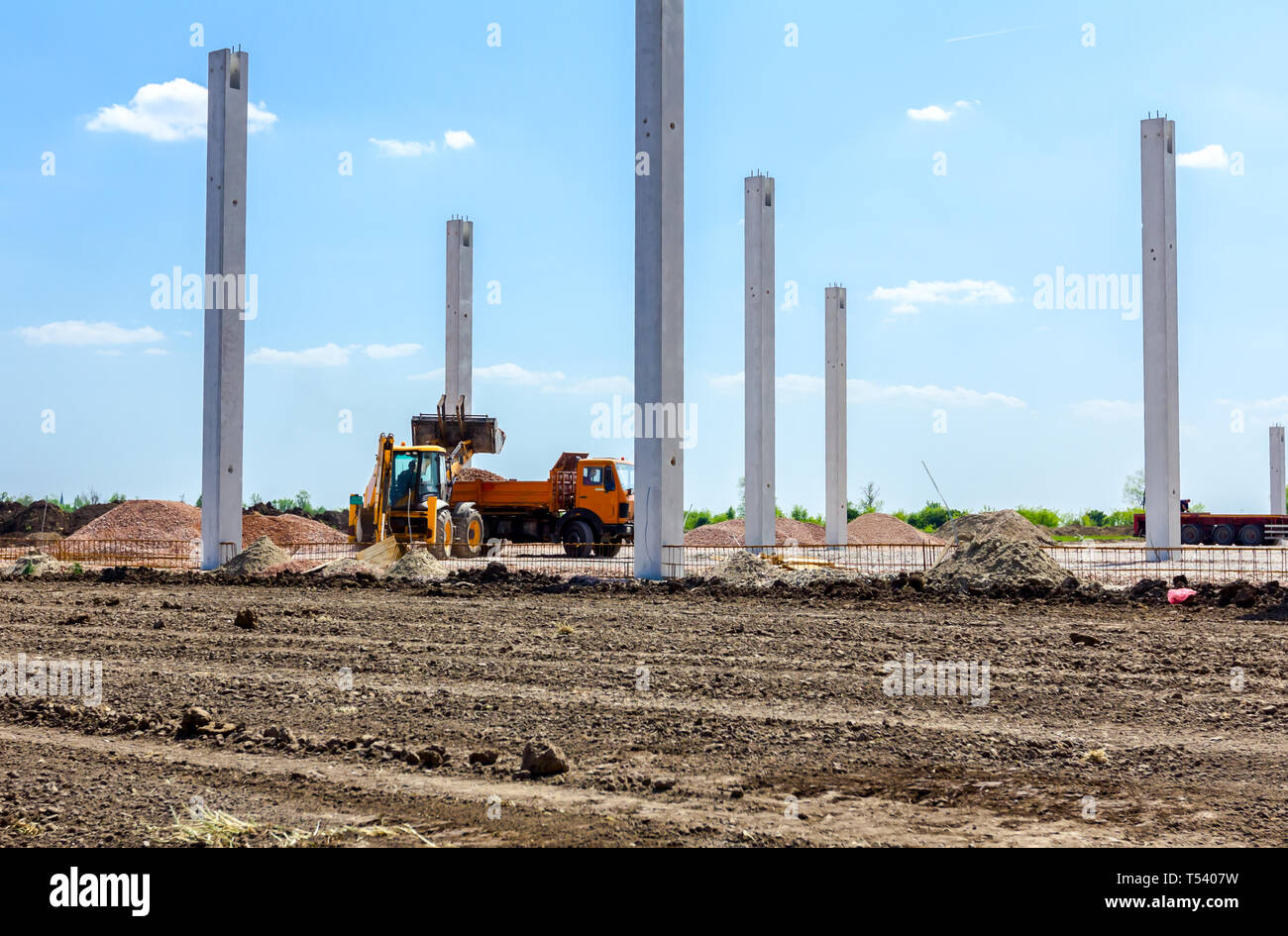 Tractor excavator is filling truck with soil at construction site ...