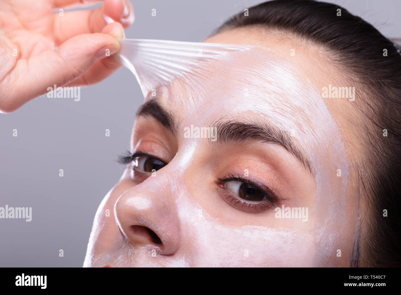 Portrait Of A Beautiful Young Woman Removing Peeling Mask From Her Face ...