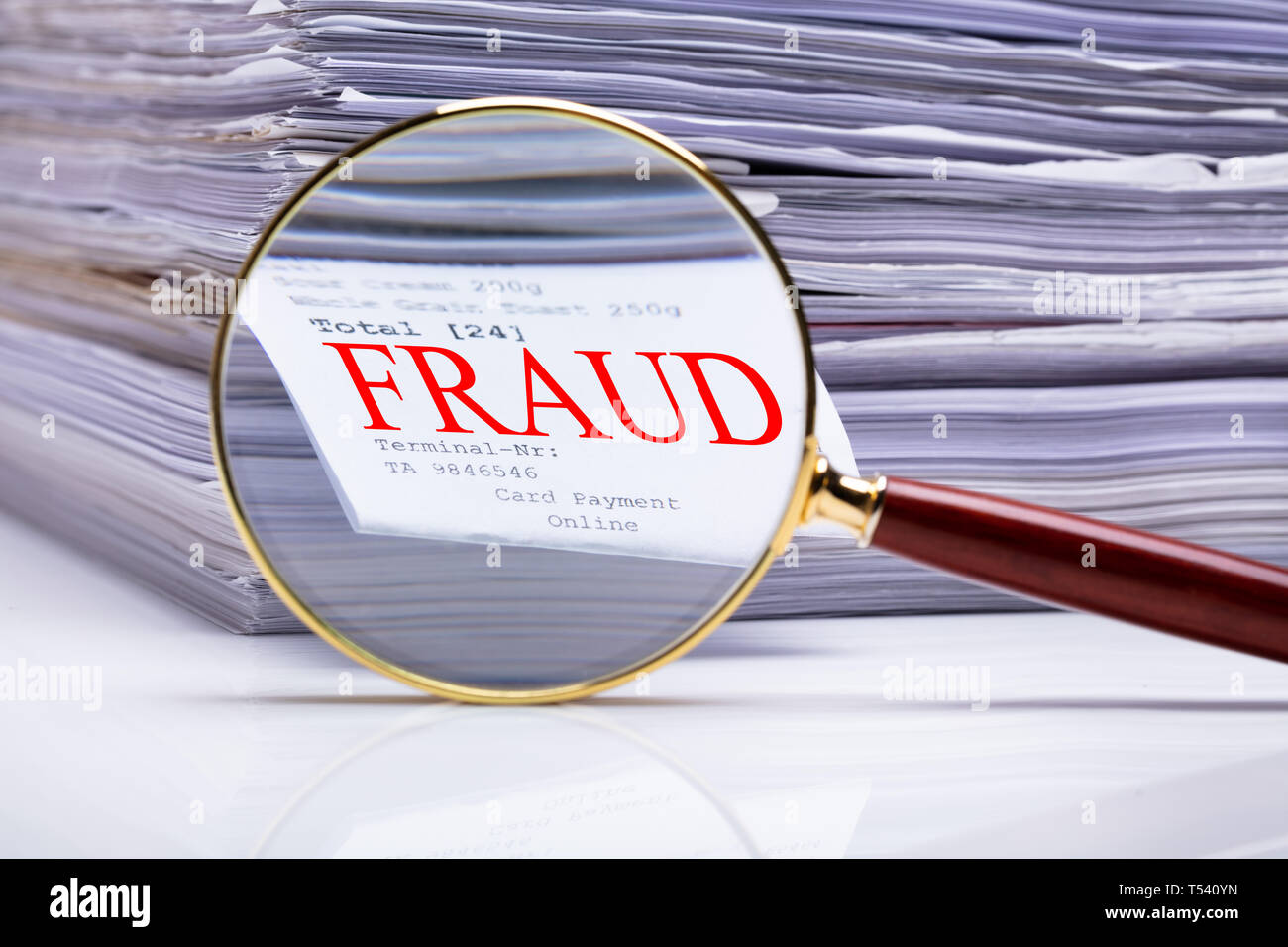 Close-up Of Magnifying Glass On Fraud Text Near Stacked Paper Over ...