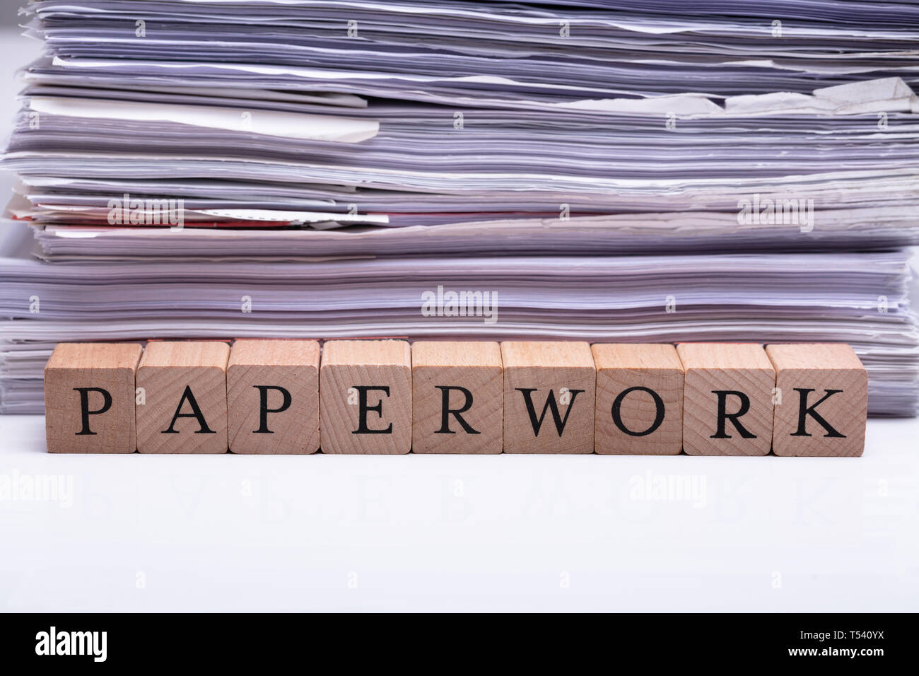 Wooden Block With Paperwork Text And Stacked Of Files On White Backdrop ...