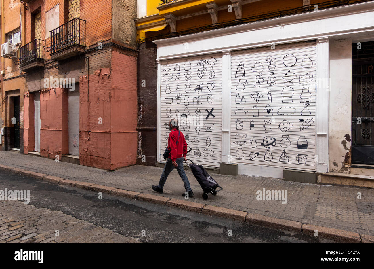 Man walking past deserted buildings in Seville Stock Photo - Alamy