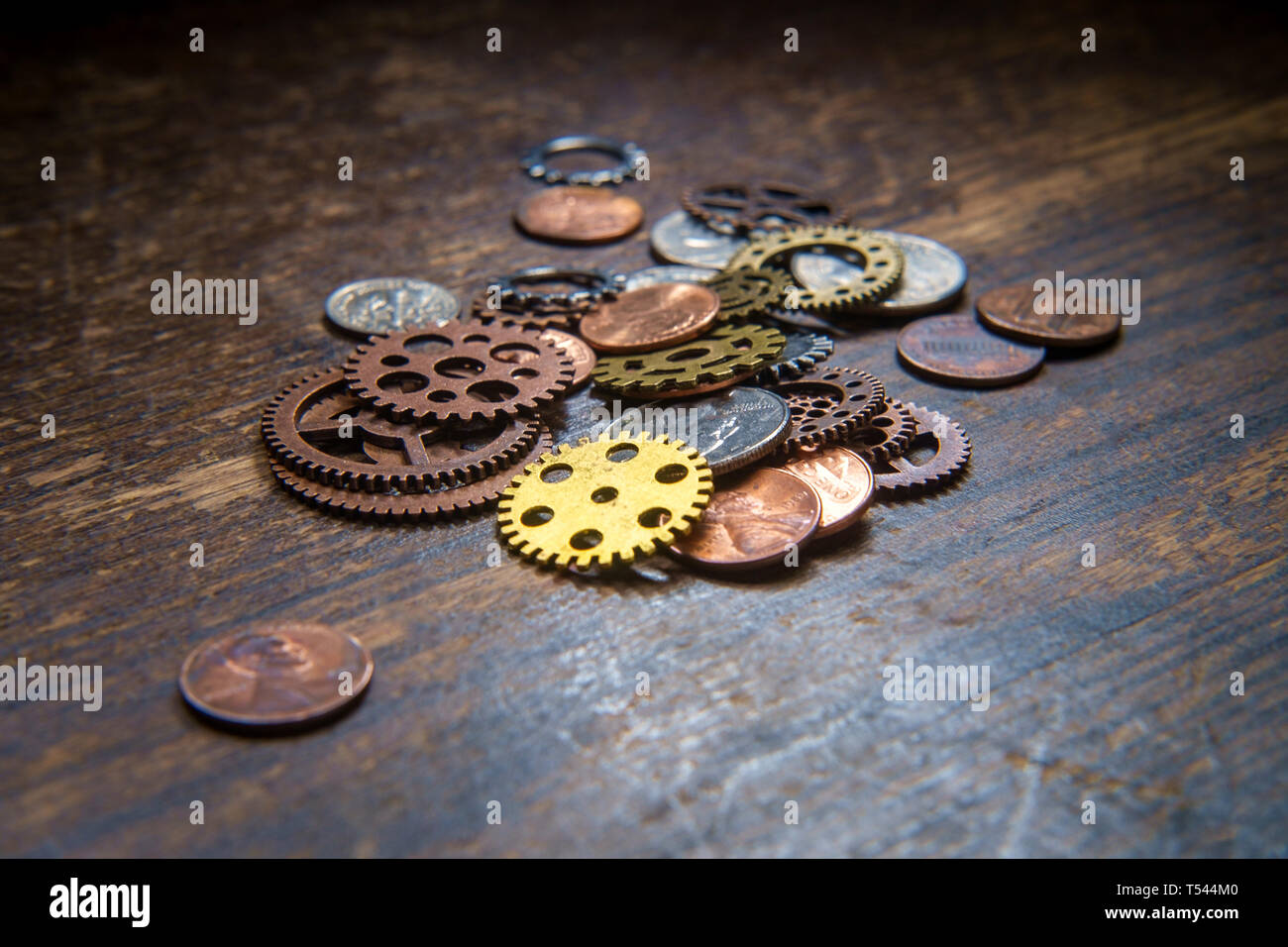 Pile of gears cogs and coins mixed together as business finance concept ...