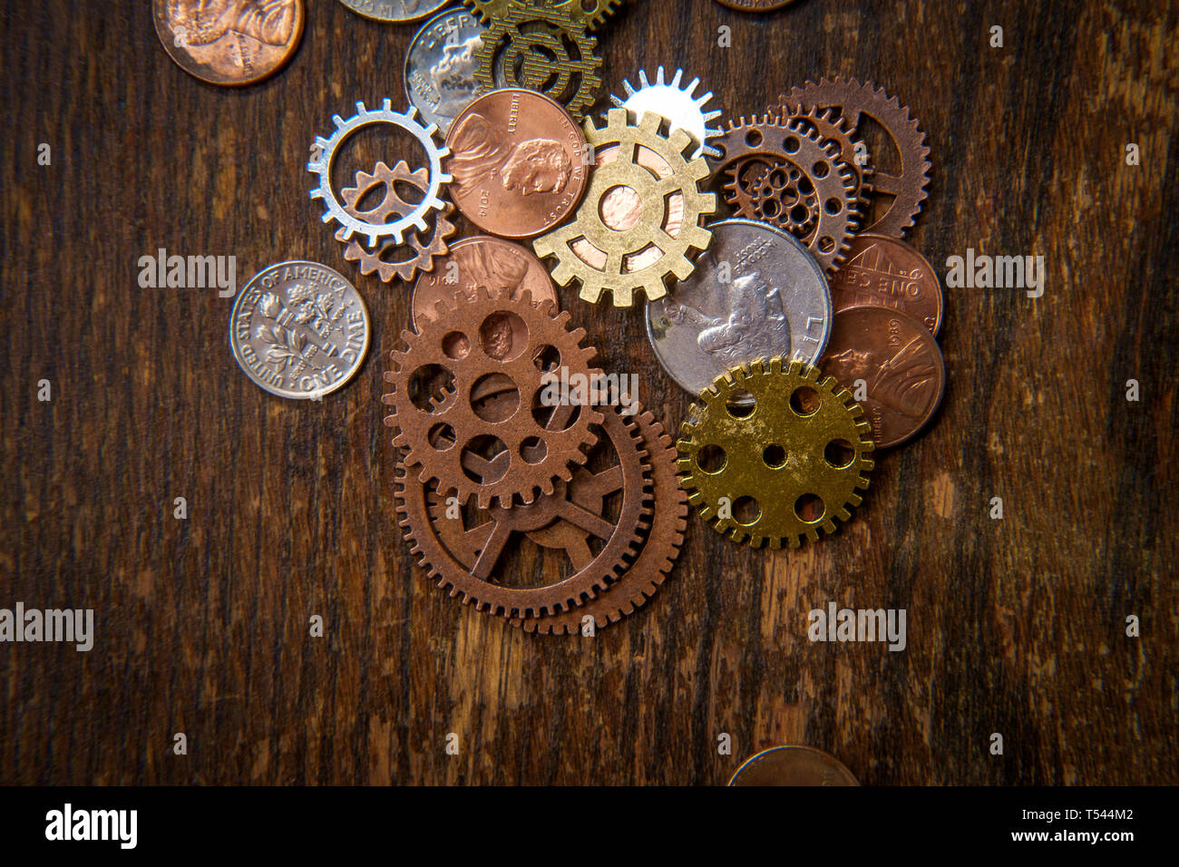 Pile of gears cogs and coins mixed together as business finance concept ...