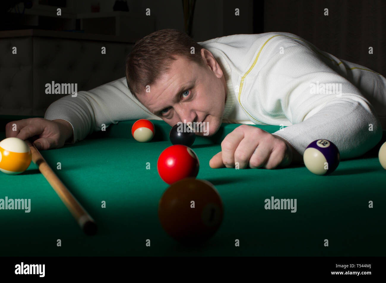 The man is playing billiards. Score the ball into the pocket. Gambler ...